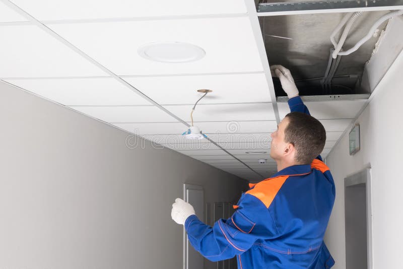 A Worker is Installing a Lighting Fixture in the Ceiling, Side View ...