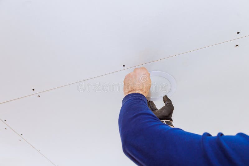 Worker Installing Lighting Fixture into Newly Constructed Ceiling in ...
