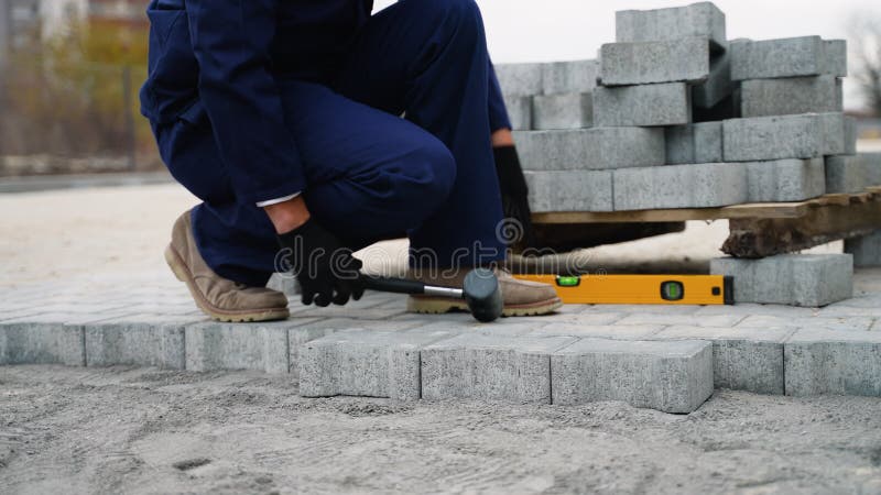 Worker Installing Paving Stones with Rubber Mallet and Level Stock ...