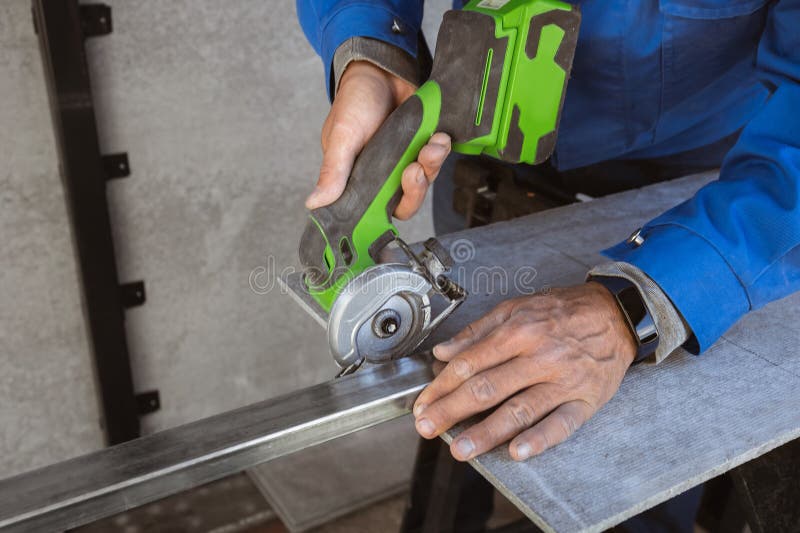 A Worker Installs an Angle Grinder with Diamond Disc for Cutting Slate at a Construction Site ...