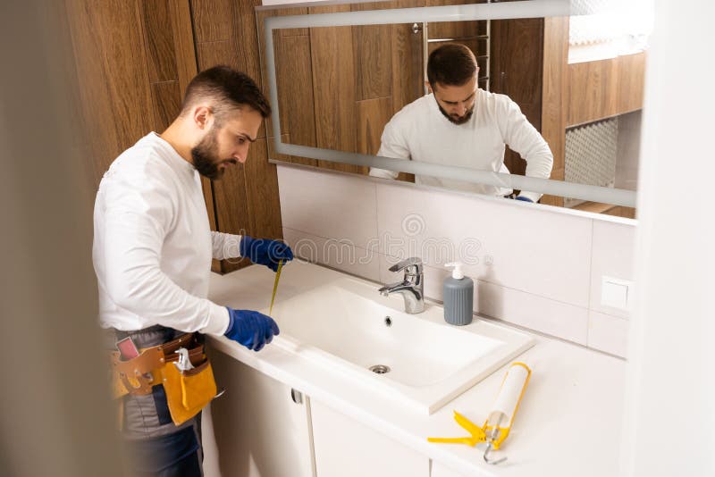 A Worker Installs a Wash Basin in a Bathroom. Stock Image - Image of ...