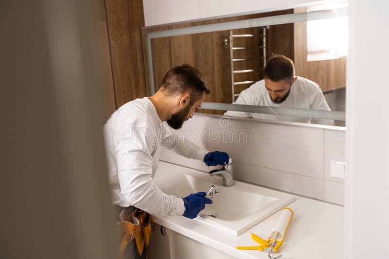 A Worker Installs a Wash Basin in a Bathroom. Stock Photo - Image of ...