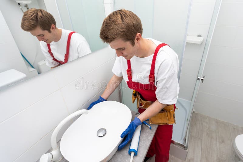 A Worker Installs a Wash Basin in a Bathroom. Stock Image - Image of ...