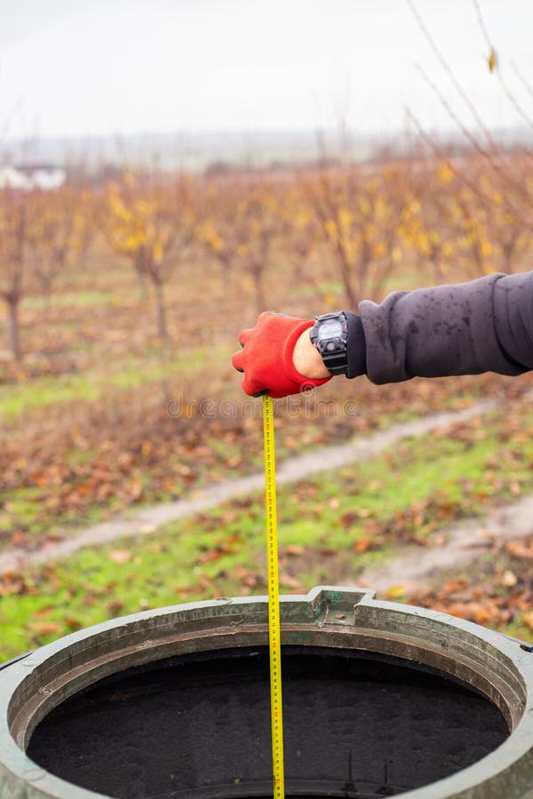 Worker Installs Water Intake Unit in Well, Measuring Well Depth ...