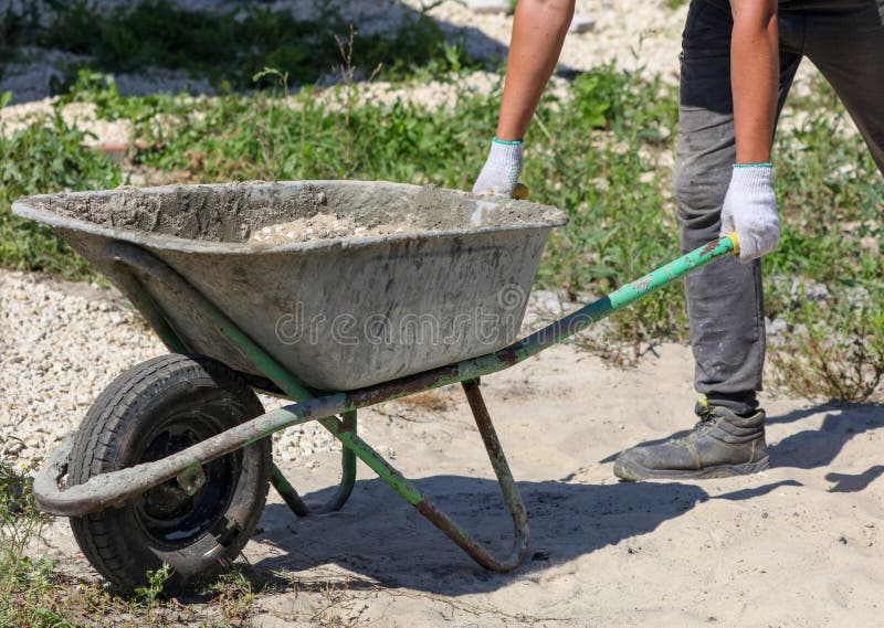A Worker Kneads a Mixture of Concrete in a Wheelbarrow at a ...