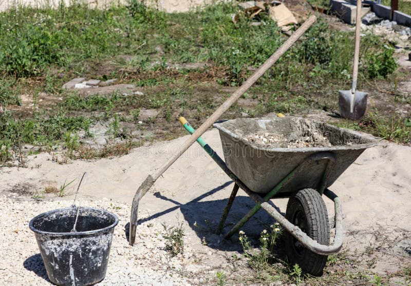 A Worker Kneads a Mixture of Concrete in a Wheelbarrow at a ...