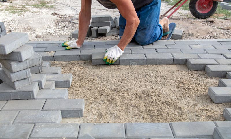 A Worker is Laying Paving Slabs in the Yard. Construction Stock Image ...