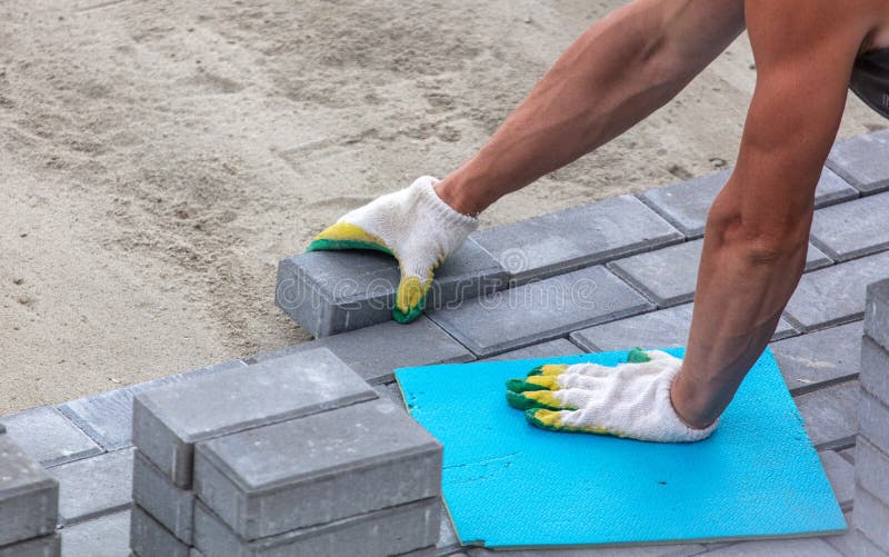A Worker is Laying Paving Slabs in the Yard. Construction Stock Photo ...