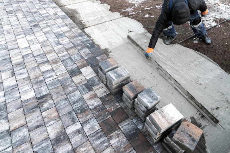 Worker Laying Paving Stones on Concrete Base for Durable Outdoor ...