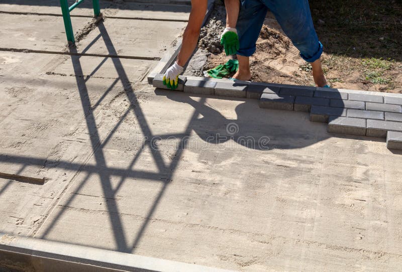 A worker lays paving slabs stock image. Image of tool - 231778011
