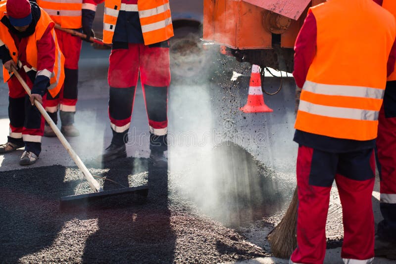 Worker Leveling Fresh Asphalt on a Road Construction Site, Industrial ...