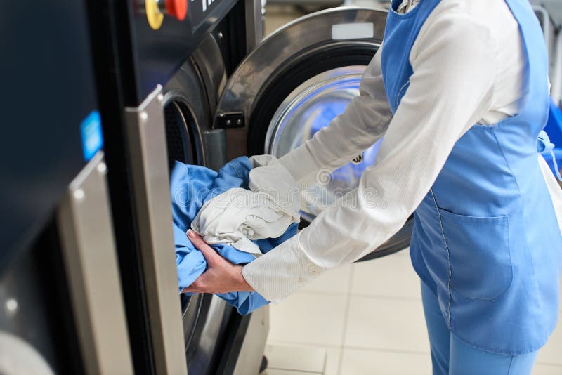 The Worker Loads the Laundry Clothing into the Washing Machine Stock ...