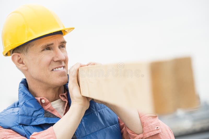Worker Looking Away while Carrying Wooden Plank Stock Image - Image of ...
