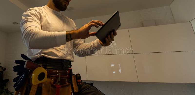 A Worker Looks at a Tablet Computer. Master with an Electronic Tablet ...