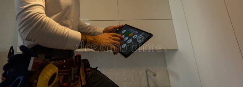 A Worker Looks at a Tablet Computer. Master with an Electronic Tablet ...