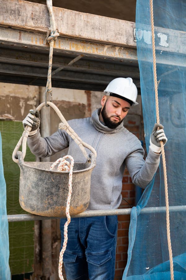 Worker Lowering Down Bucket with Construction Mortar Stock Photo ...