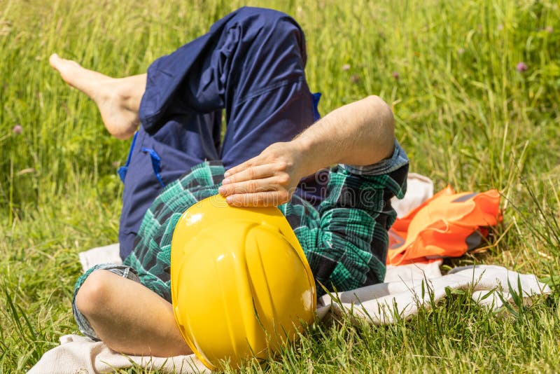 Worker Relaxes Lying on a Meadow with a Helmet and in Working Clothes ...
