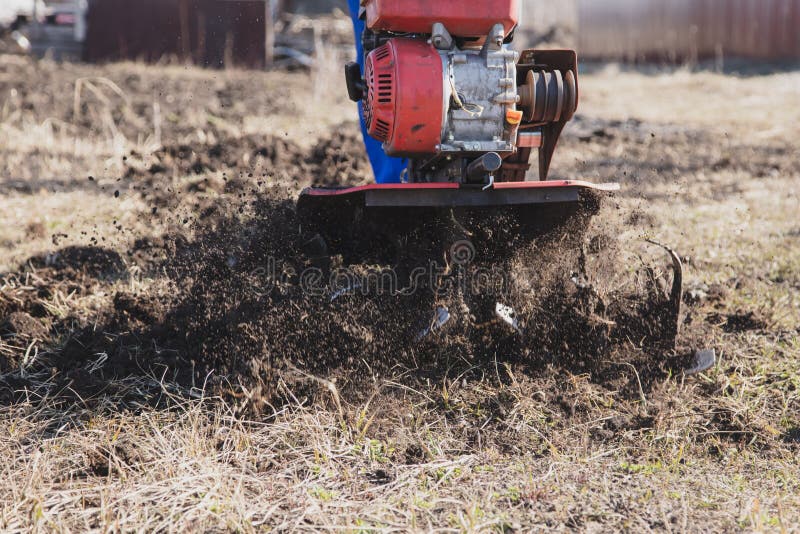 Worker with a Machine Cultivator Digs the Soil in the Garden Stock ...