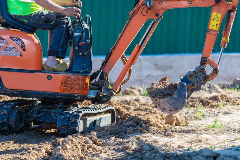 A Worker on a Minitractor Rakes the Earth with a Bucket. Land Works ...