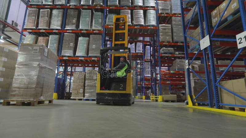 Worker on a Modern Forklift. Working in a Large Modern Warehouse Stock ...
