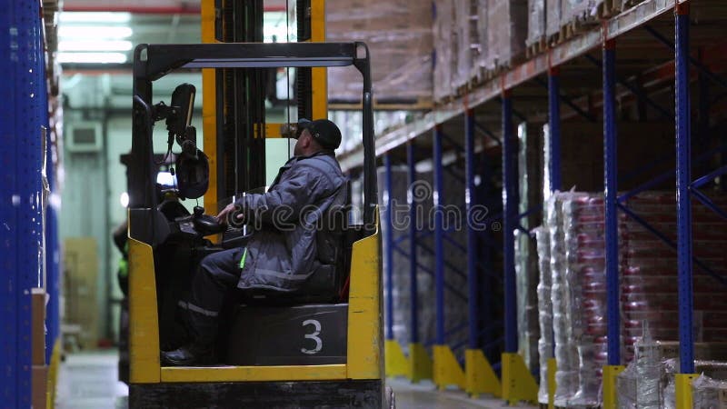 Worker with Forklift in the Warehouse. the Worker Walks through the ...