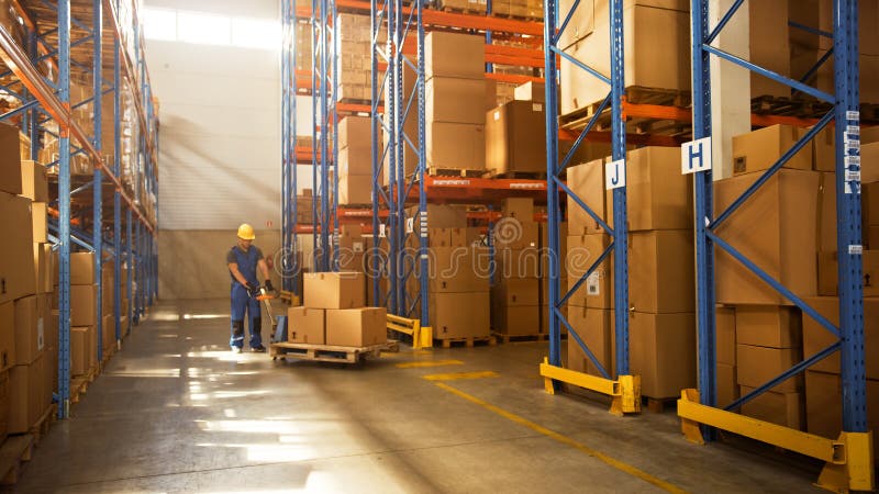 Worker Moves Cardboard Boxes Using Manual Pallet Truck, Walking between ... Worker Moves Cardboard Boxes Using Manual Pallet Truck, Walking between ...