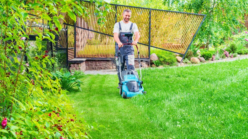 A Worker Mows the Lawn with an Electric Lawn Mower. the Man is Doing ...