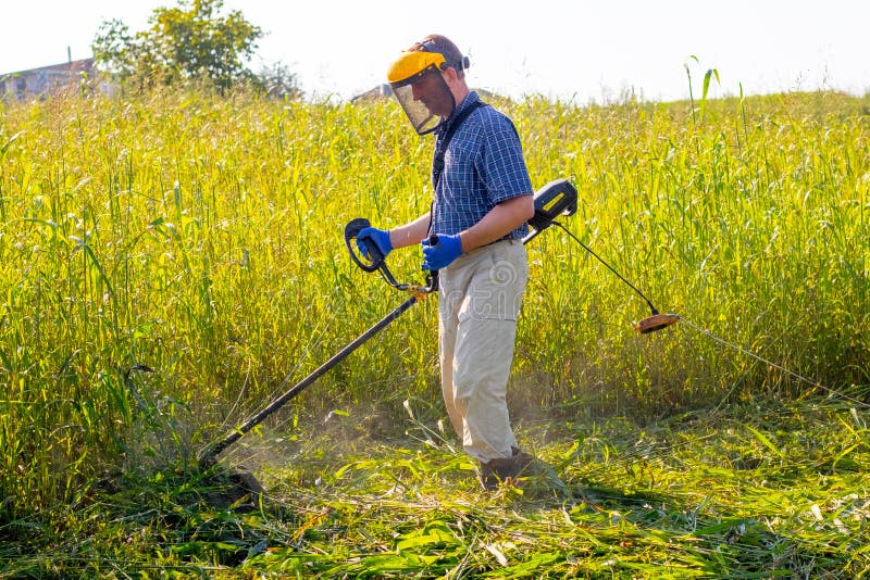 A Worker Mows Tall Grass with an Electric Trimmer Stock Photo - Image ...