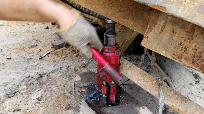 Worker Operating Red Hydraulic Jack in a Construction Setting Stock ...