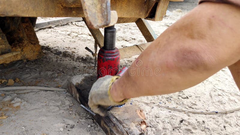 Worker Operating Red Hydraulic Jack in a Construction Setting Stock ...