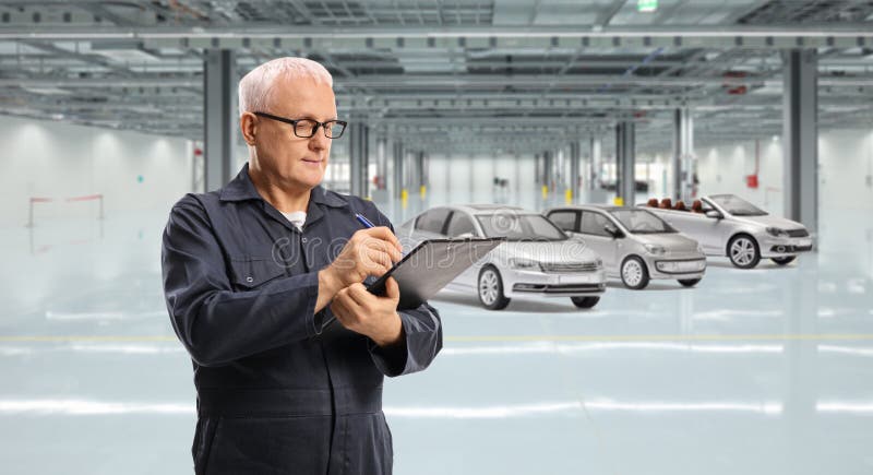 Worker in an Overall Uniform Writing a Document in a Car Garage Stock ...