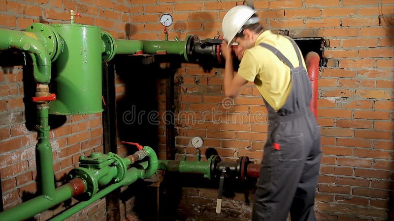 A Worker in Overalls Opens the Water Valve. the Man Includes Heating in ...