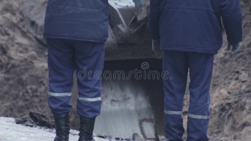 A Worker in Overalls Watches the Process of Digging a Hole with an ...