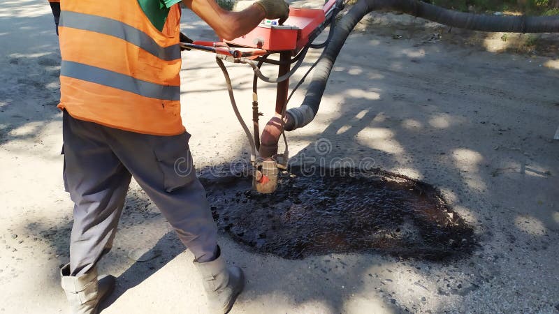 Worker Patching Up the Road, Repairing Holes in the Road Stock Photo ...