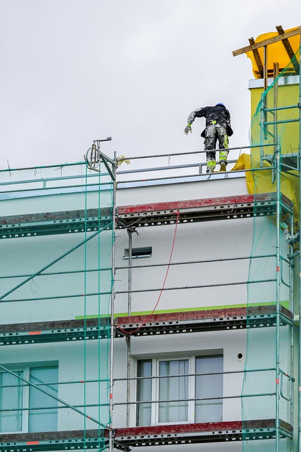A Worker Performs Dangerous Activities on the Roof of a High House ...