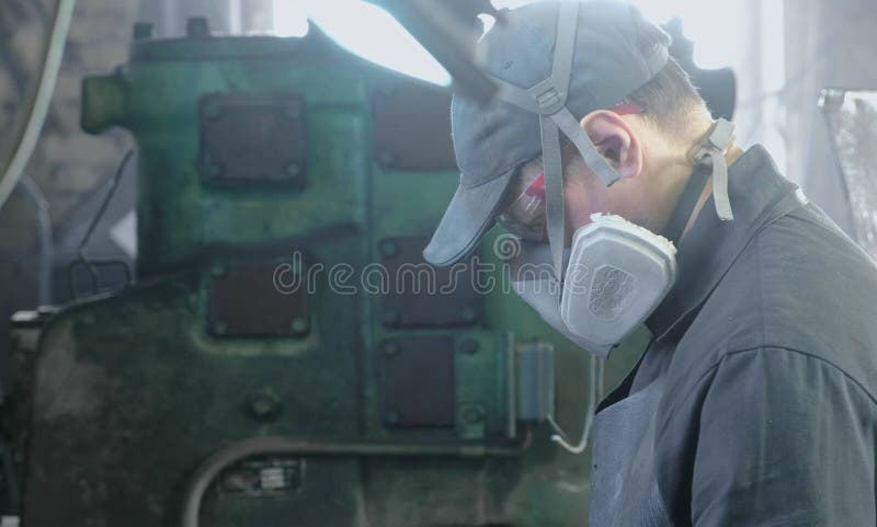 Worker Performs His Job in a Protective Mask on His Face in the Shop ...