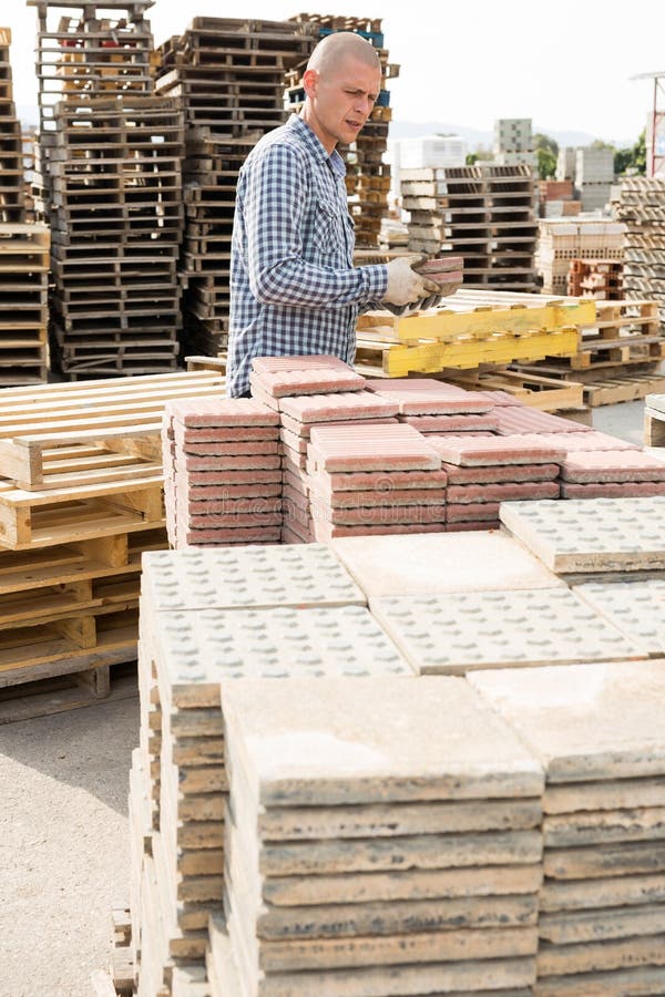 Worker Places Paving Slabs on a Pallet in Building Materials Warehouse ...