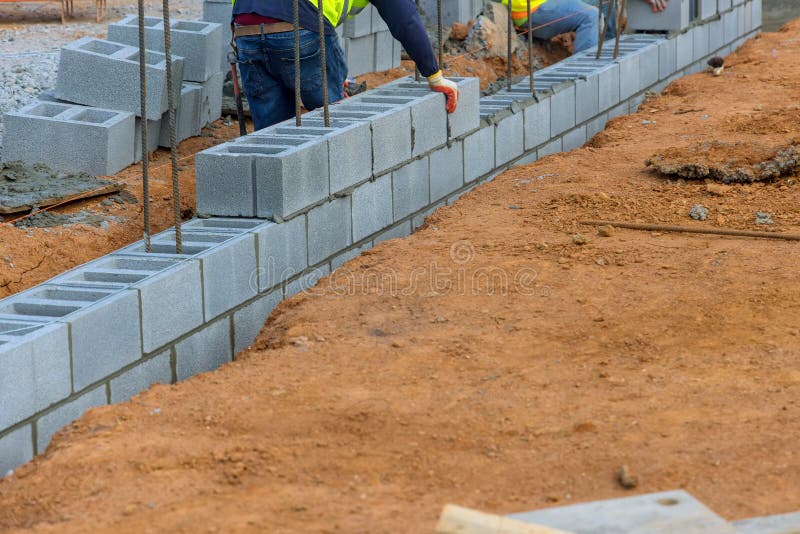 Worker Placing Cement Blocks Along Another Row of Bricks in a ...
