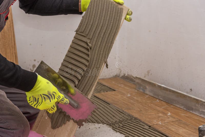 Worker Placing Ceramic Floor Tiles on Adhesive Surface, Leveling with ...