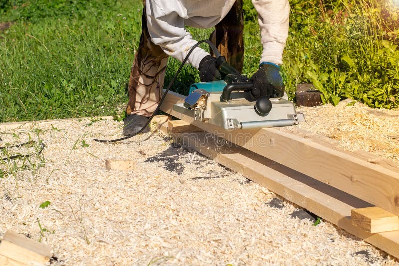 A Worker Planes a Board with a Power Tool, Chips are Flying Stock Photo ...