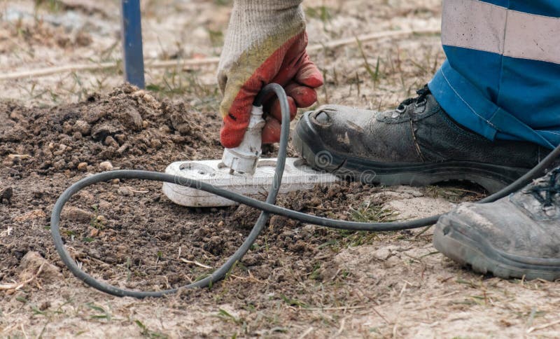 A Worker Plugs the Plug into an Extension Socket at a Construction Site ...