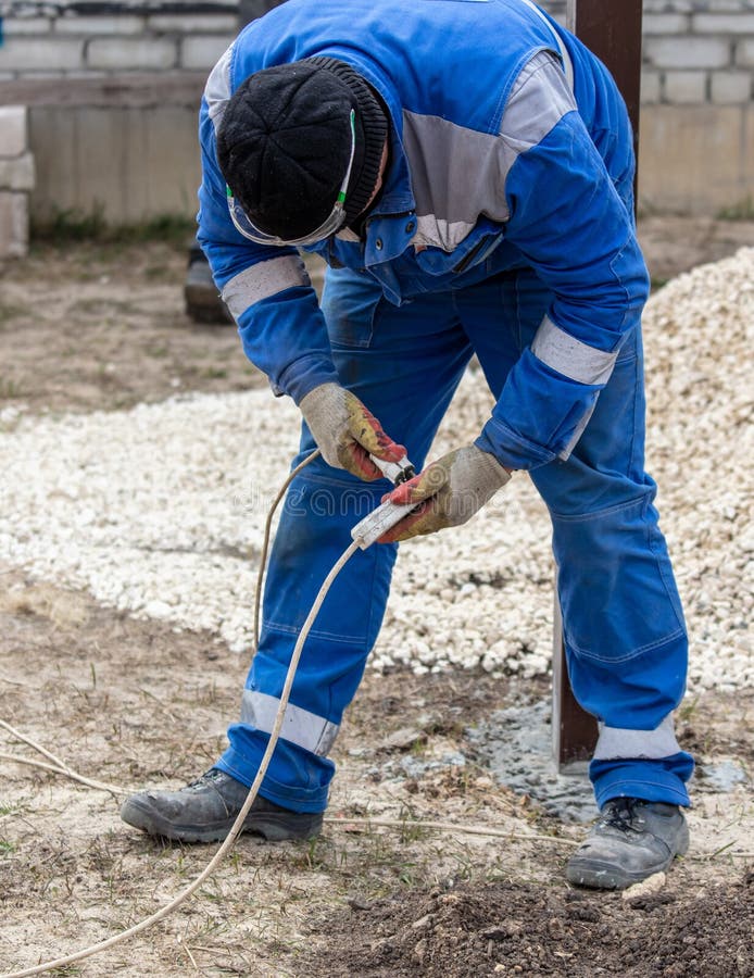 A Worker Plugs the Plug into an Extension Socket at a Construction Site ...