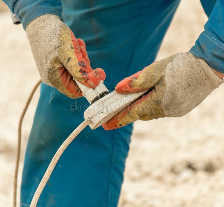 A Worker Plugs the Plug into an Extension Socket at a Construction Site ...