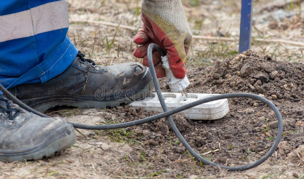 A Worker Plugs the Plug into an Extension Socket at a Construction Site ...
