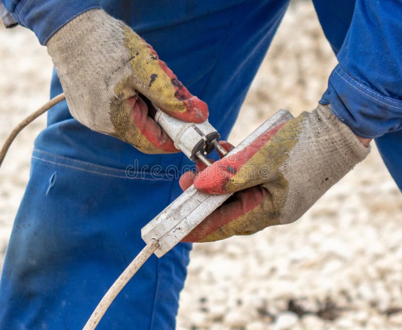 A Worker Plugs the Plug into an Extension Socket at a Construction Site ...