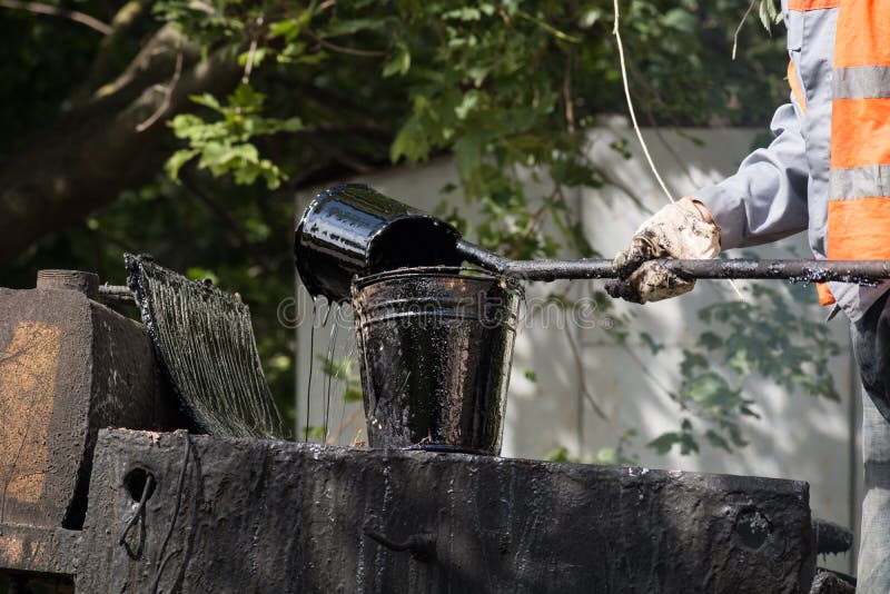 The Worker Pours Hot Bitumen into the Bucket. Stock Image - Image of ...