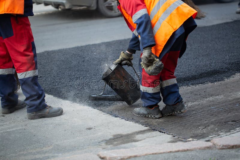 A Worker Pours Liquid Asphalt, Molten Bitumen from a Bucket of Resin ...