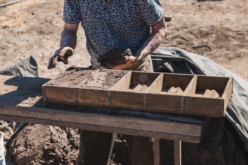 Worker Pours the Mixture of Mud, Sand and Sawdust Over Molds for Making ...