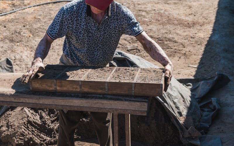 Worker Pours the Mixture of Mud, Sand and Sawdust Over Molds for Making ...