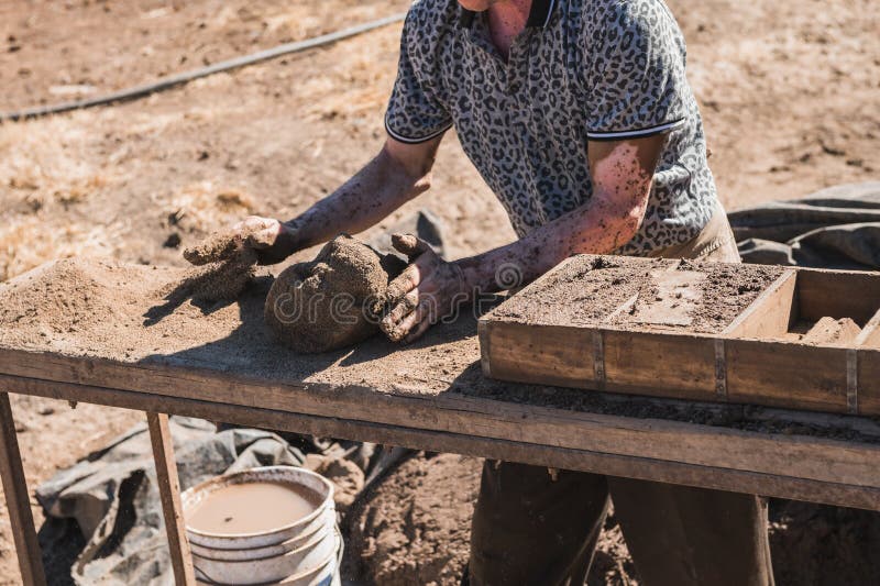 Worker Pours the Mixture of Mud, Sand and Sawdust Over Molds for Making ...